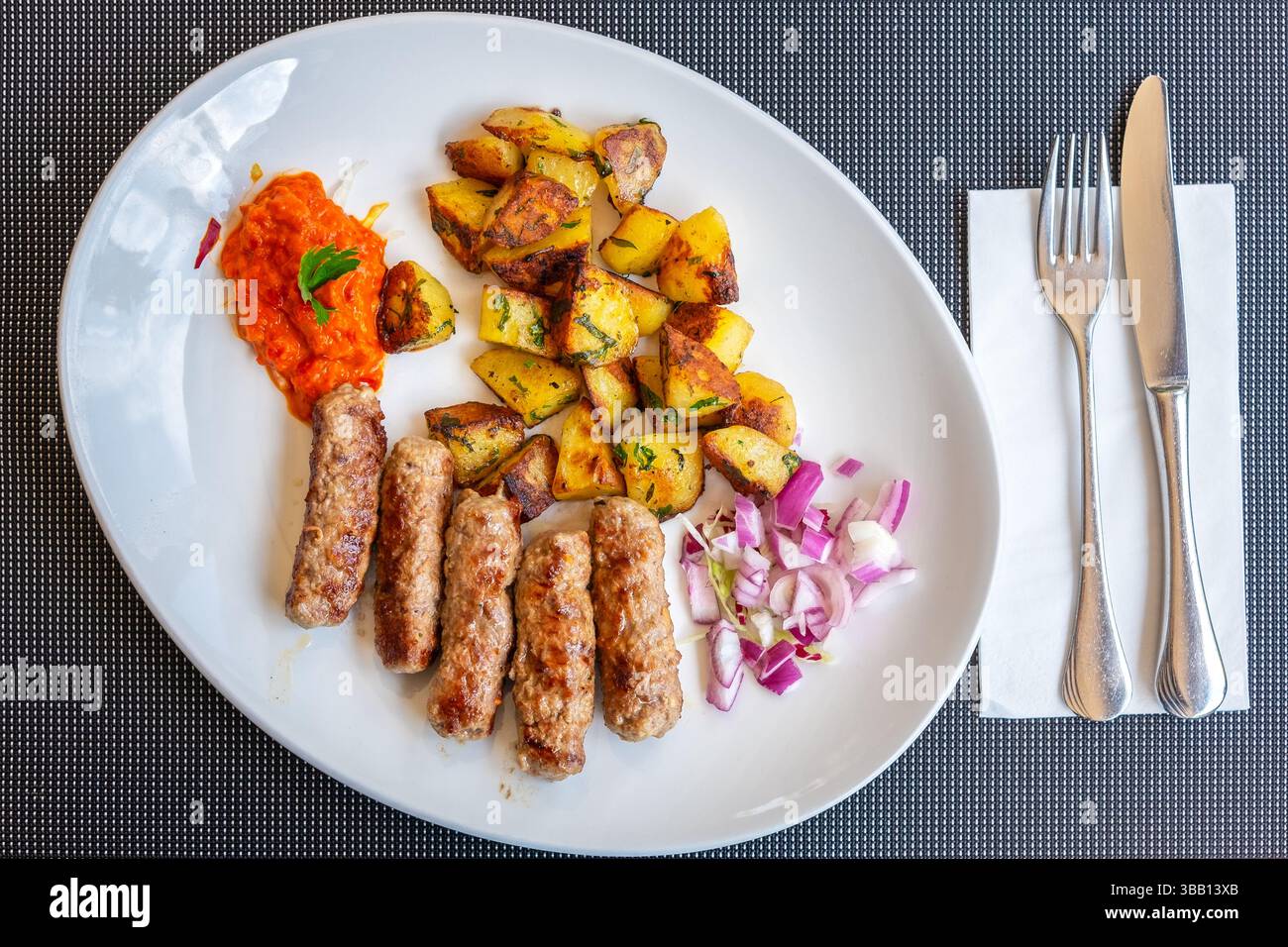 Traditional cevapcici (sausages) with roasted potatoes and fresh onions ...