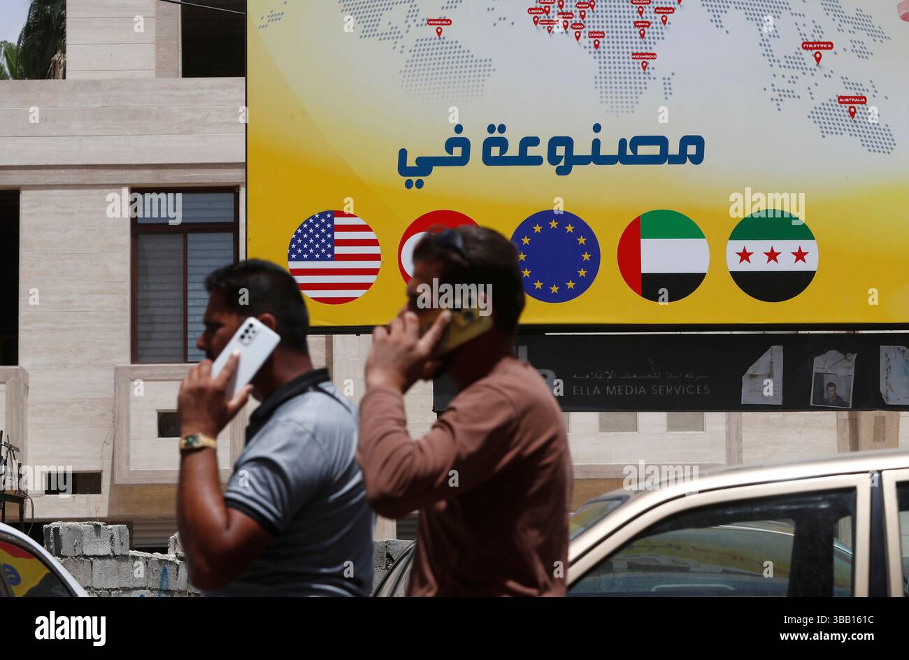 Syrian men speak on their mobile phones, as they pass on a street in Damascus, Syria, Wednesday ...