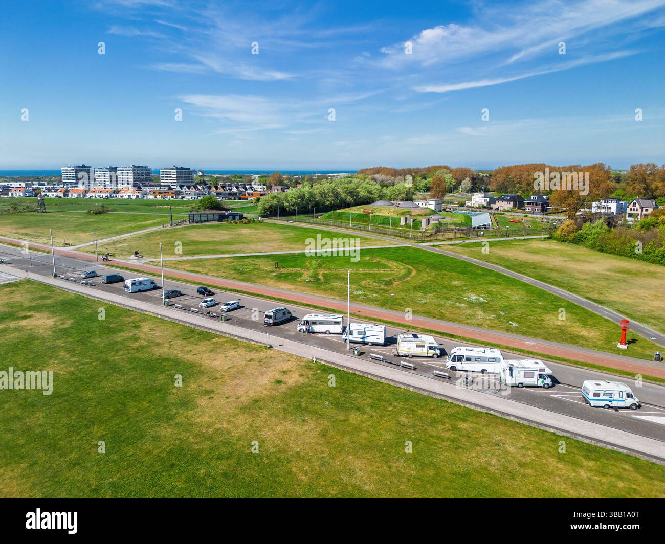 Aerial view of a green open field with a row of camper vans parked ...