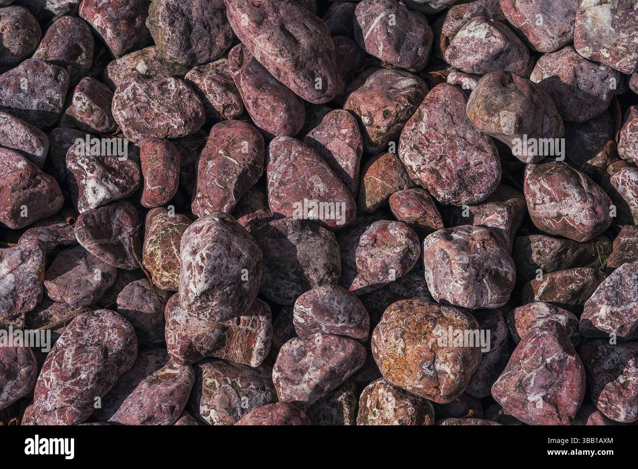 Smooth pebbles in shades of purple and gray are densely packed on the ...