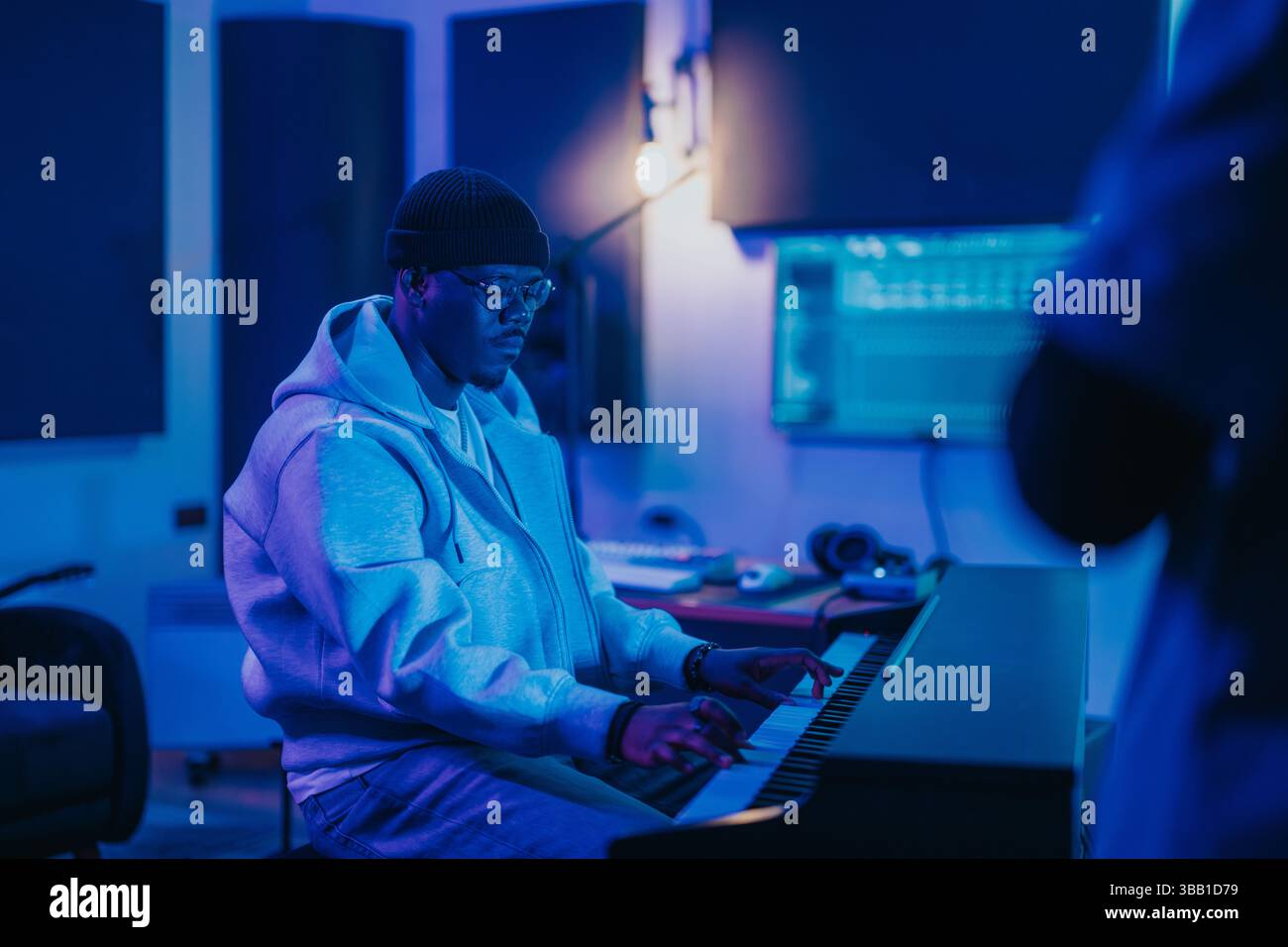 A focused musician plays the piano in a high-tech music studio ...