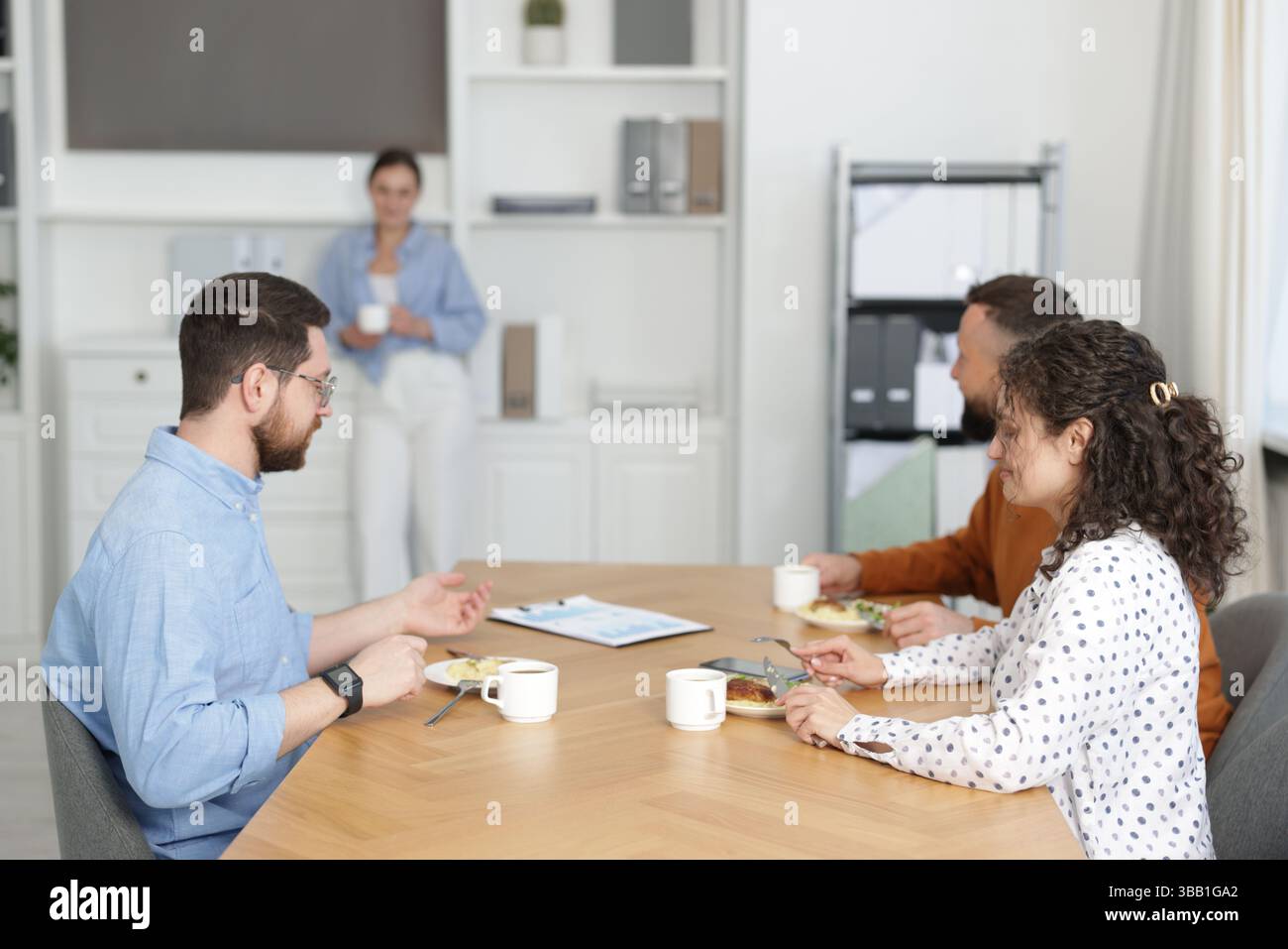 Colleagues eating and chatting during lunch break in office Stock Photo ...