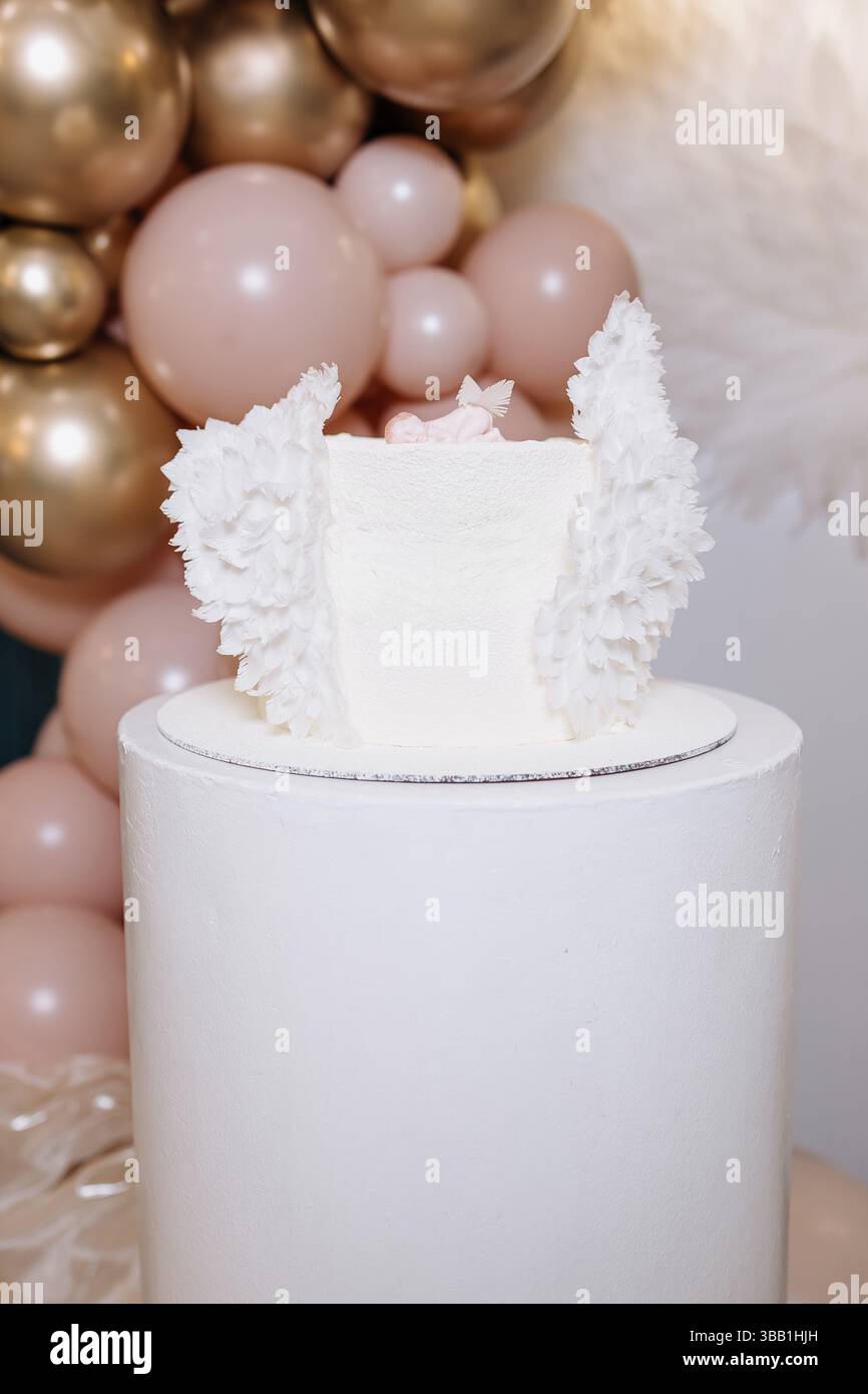 White cake for celebrating a child's baptism. Sweet cake with white wings. Photo zone for a ...