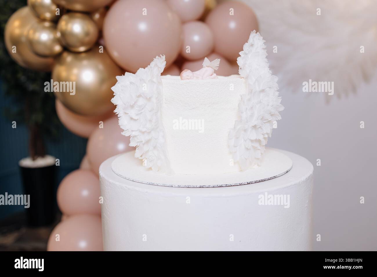 White cake for celebrating a child's baptism. Sweet cake with white wings. Photo zone for a ...