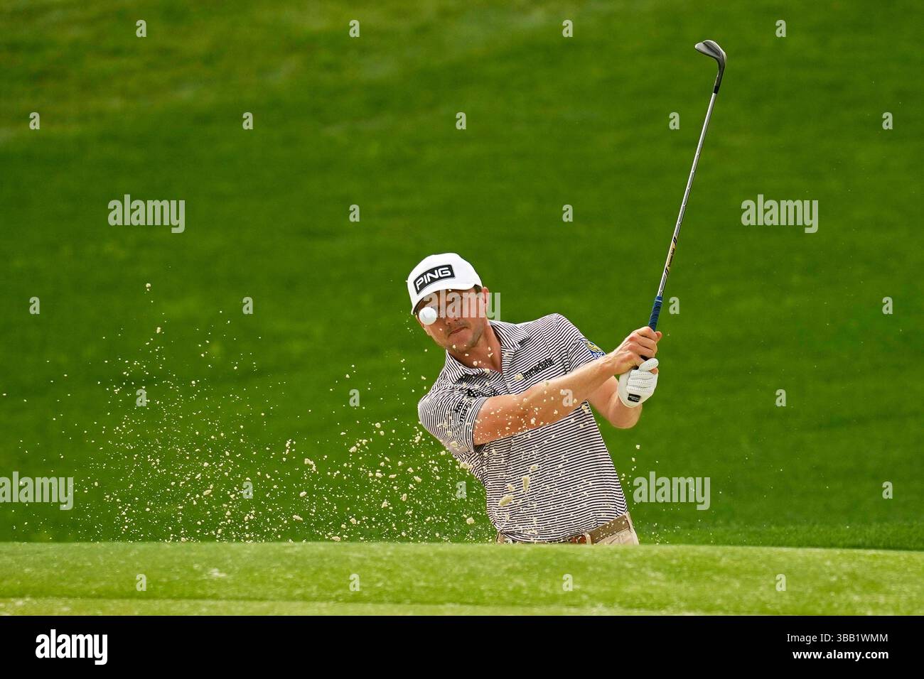Mackenzie Hughes, of Canada, hits from the bunker on the first hole ...
