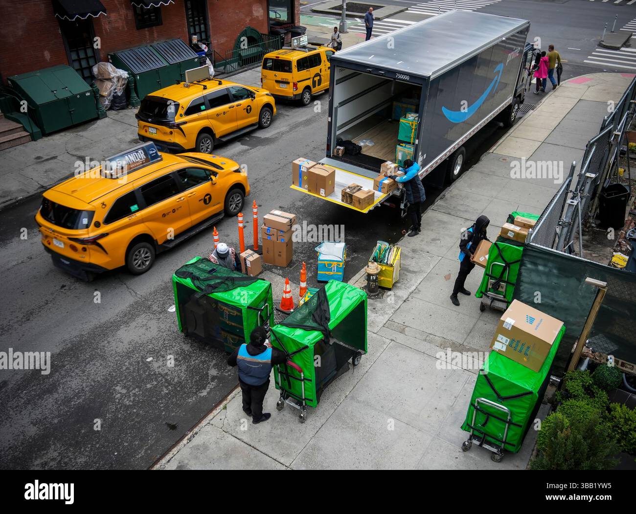Workers sort Amazon deliveries for distribution out of a large truck in ...