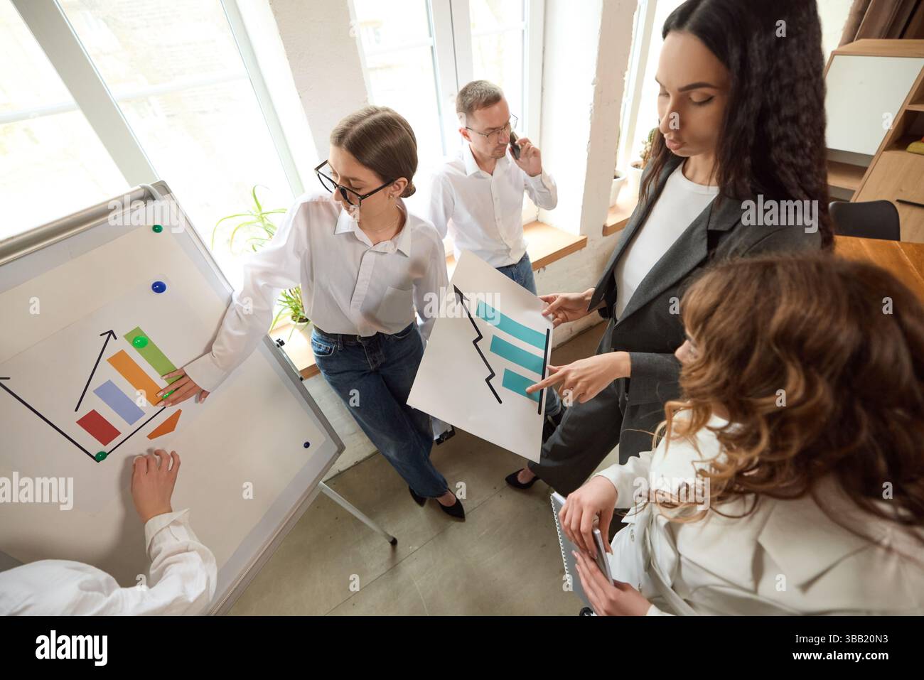 Business team discusses charts and data near whiteboard in modern ...