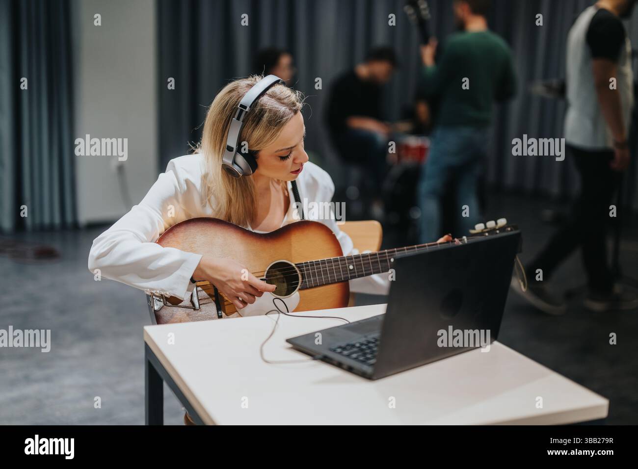 Female guitarist performing with a band during a rehearsal session in a ...
