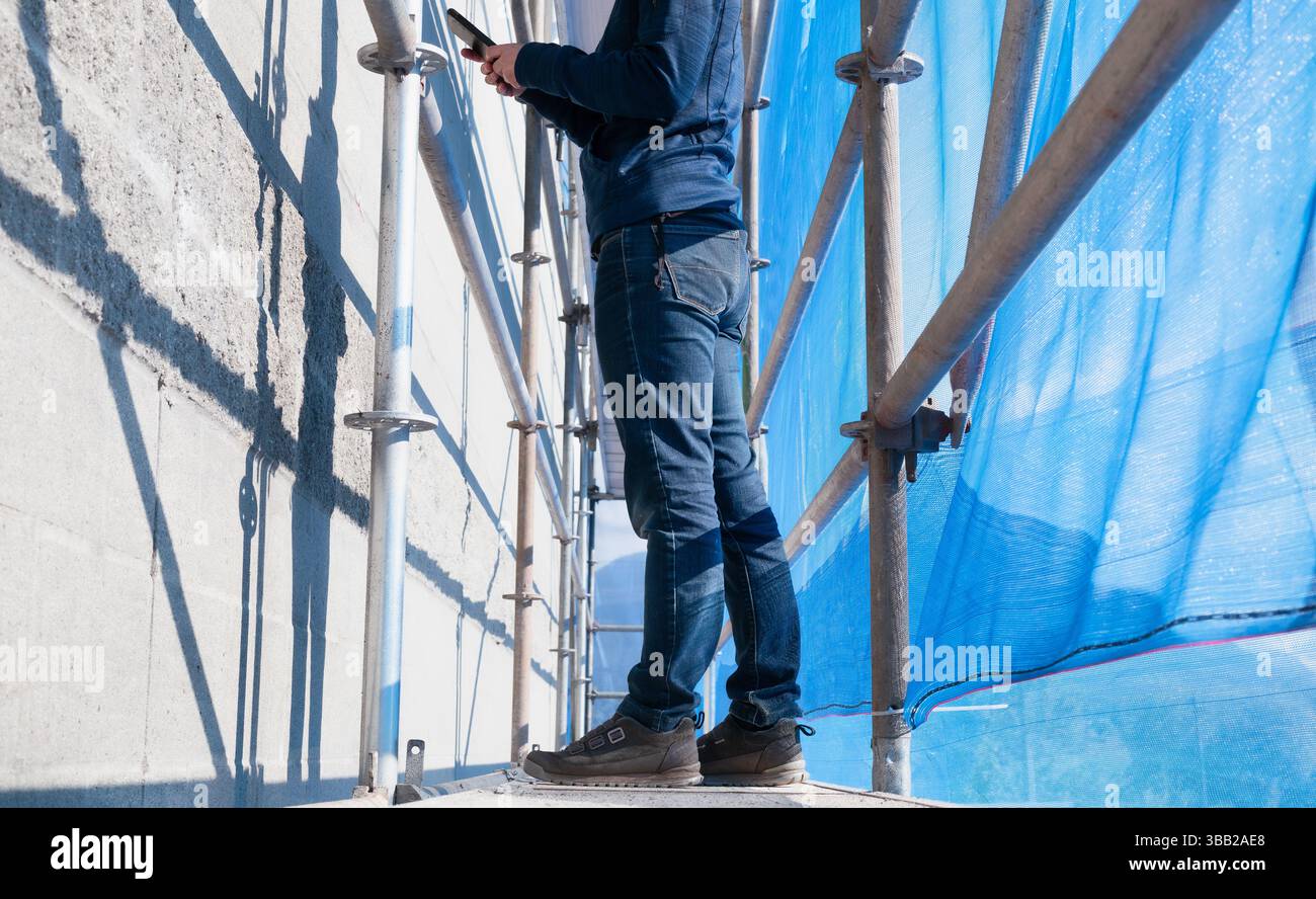 Engineer standing inside scaffolding with scaffold netting. Side view ...