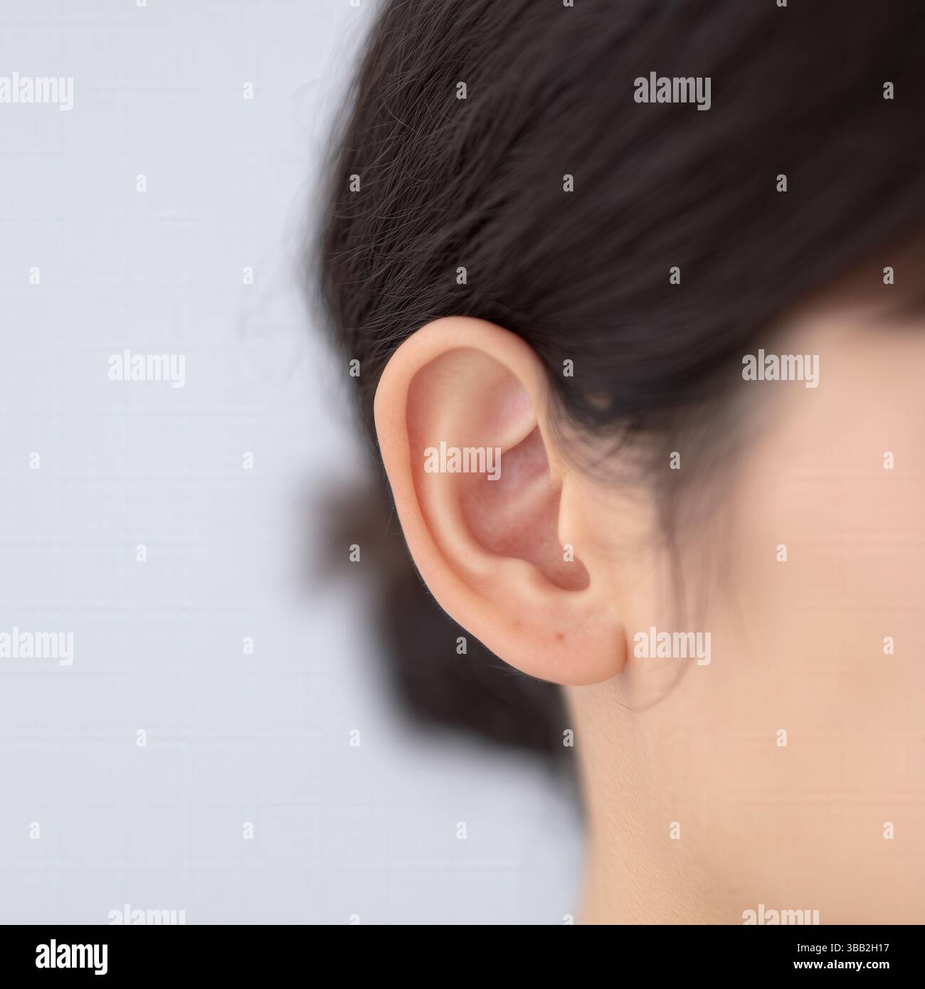 Close-up view of a person's ear and adjacent neck and hair. The ear is ...