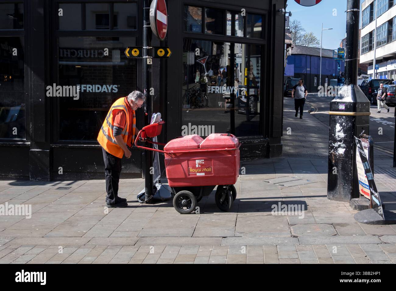 Royal Mail postman unlocking trolly from no entry post, High Street ...