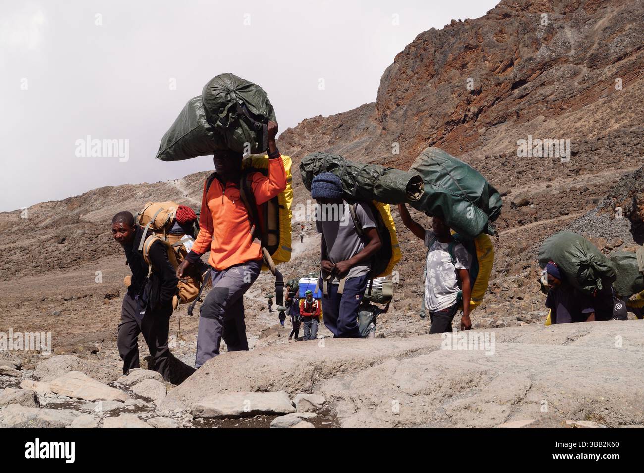 A group of porters ascends a rocky path on Mount Kilimanjaro, Tanzania ...