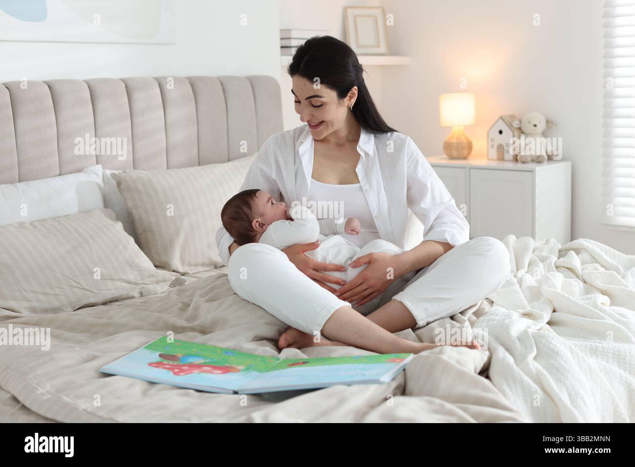 Bedtime. Mother with her cute little baby on bed at home Stock Photo ...
