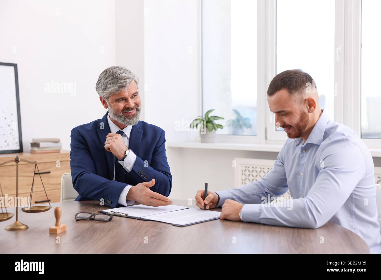 Client signing notarial paperwork during meeting with lawyer at wooden ...