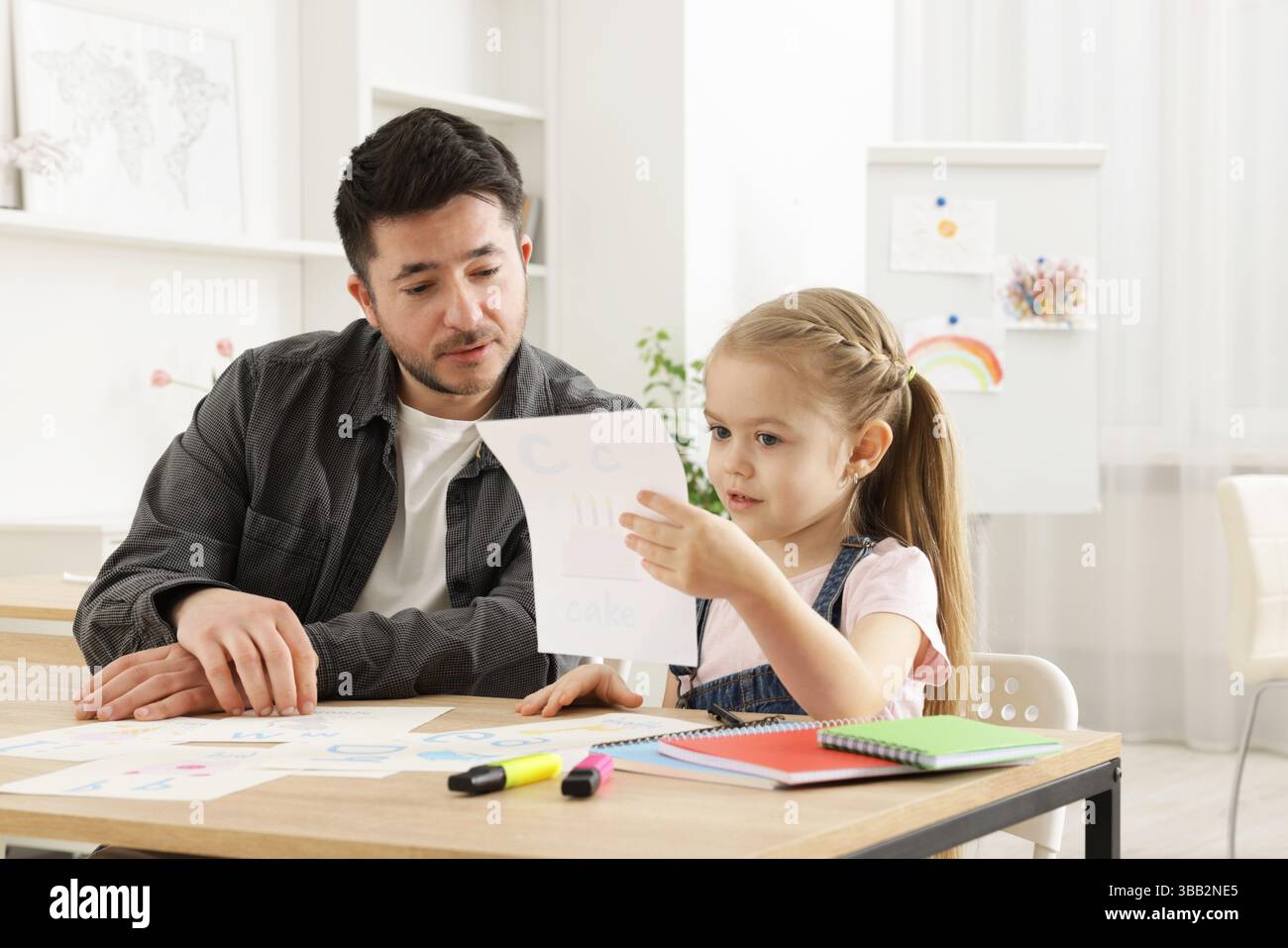 Teacher having lesson with little girl at desk indoors Stock Photo - Alamy