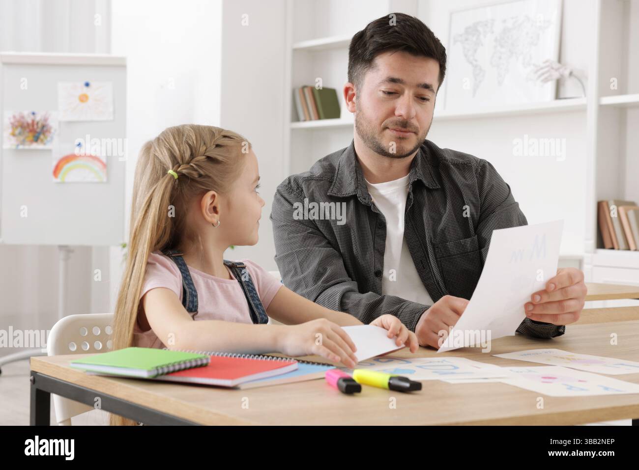 Teacher having lesson with little girl at desk indoors Stock Photo - Alamy
