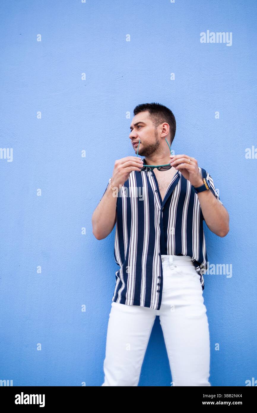 A stylish young man, dressed in a trendy striped shirt and crisp white ...