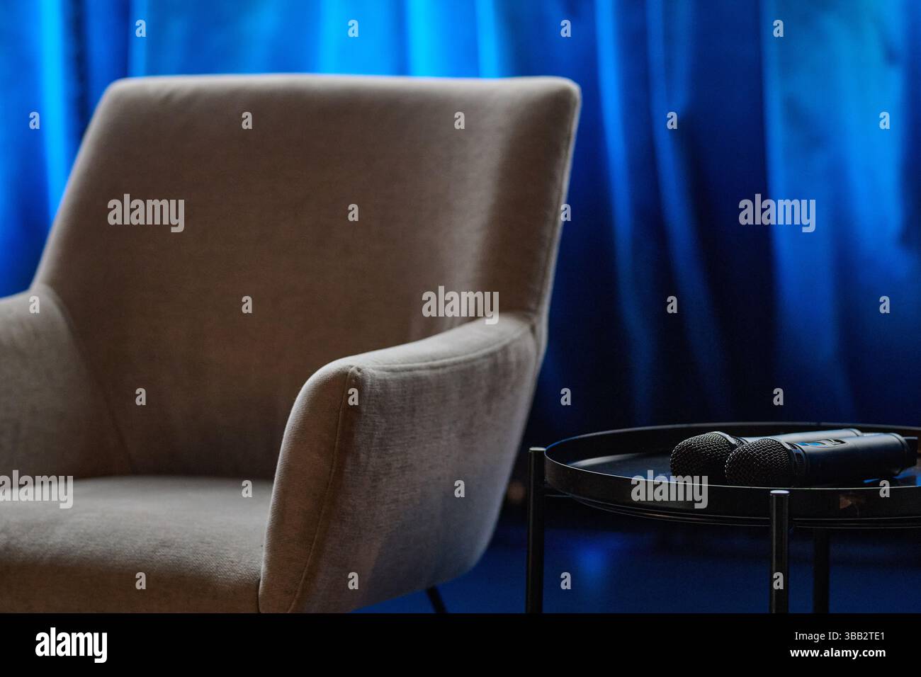 Cozy interview stage setup with one gray armchair and two wireless ...