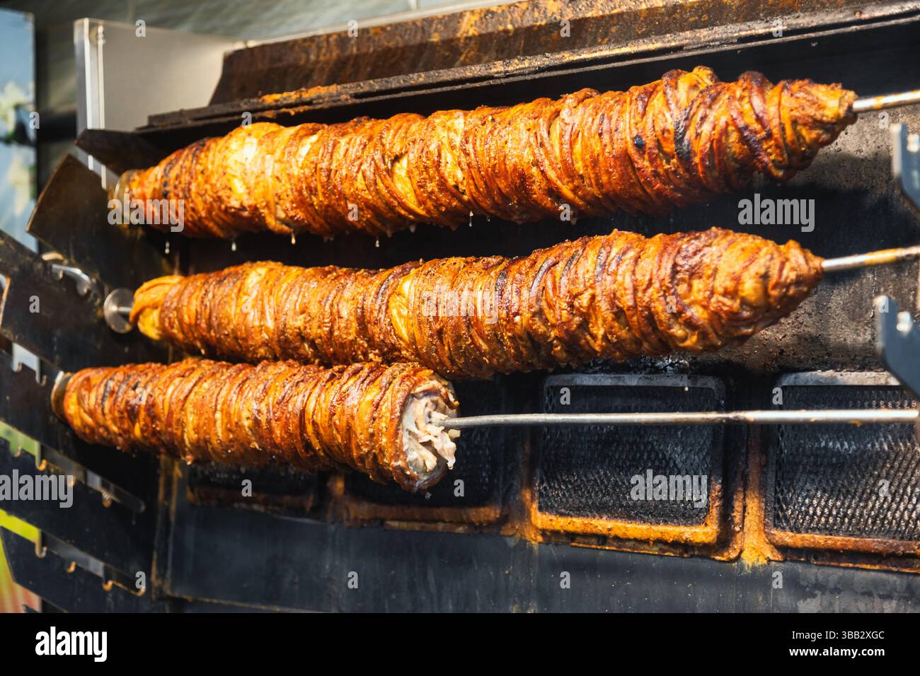 Seasoned kokorec skewers made of lamb intestines roast on a rotisserie ...