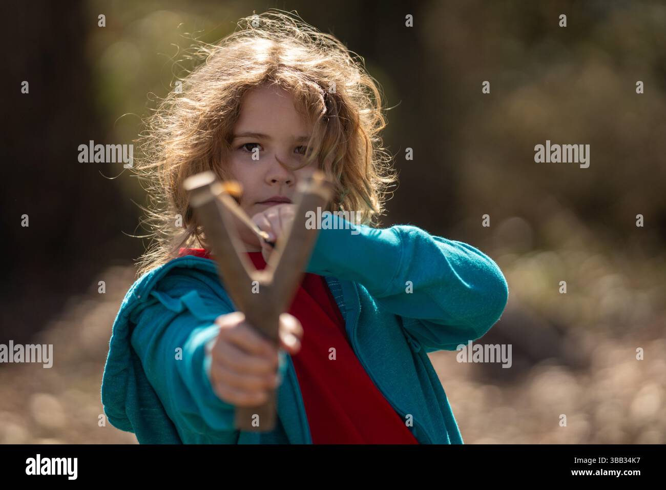 Slingshot in kids hand. Child holding catapult. Kid aiming with sling ...