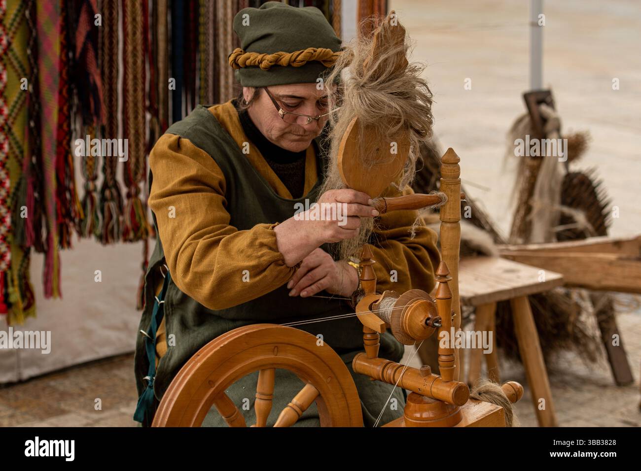 Woman in traditional clothes working on an ancient wooden weaving loom ...