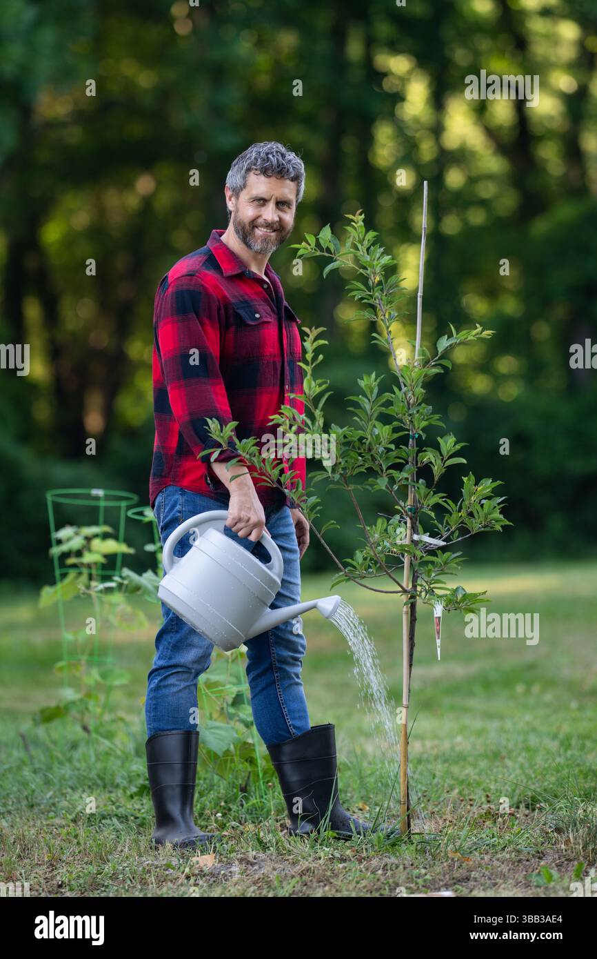 Man growing plants in the garden. Farmer watering tree in the home ...