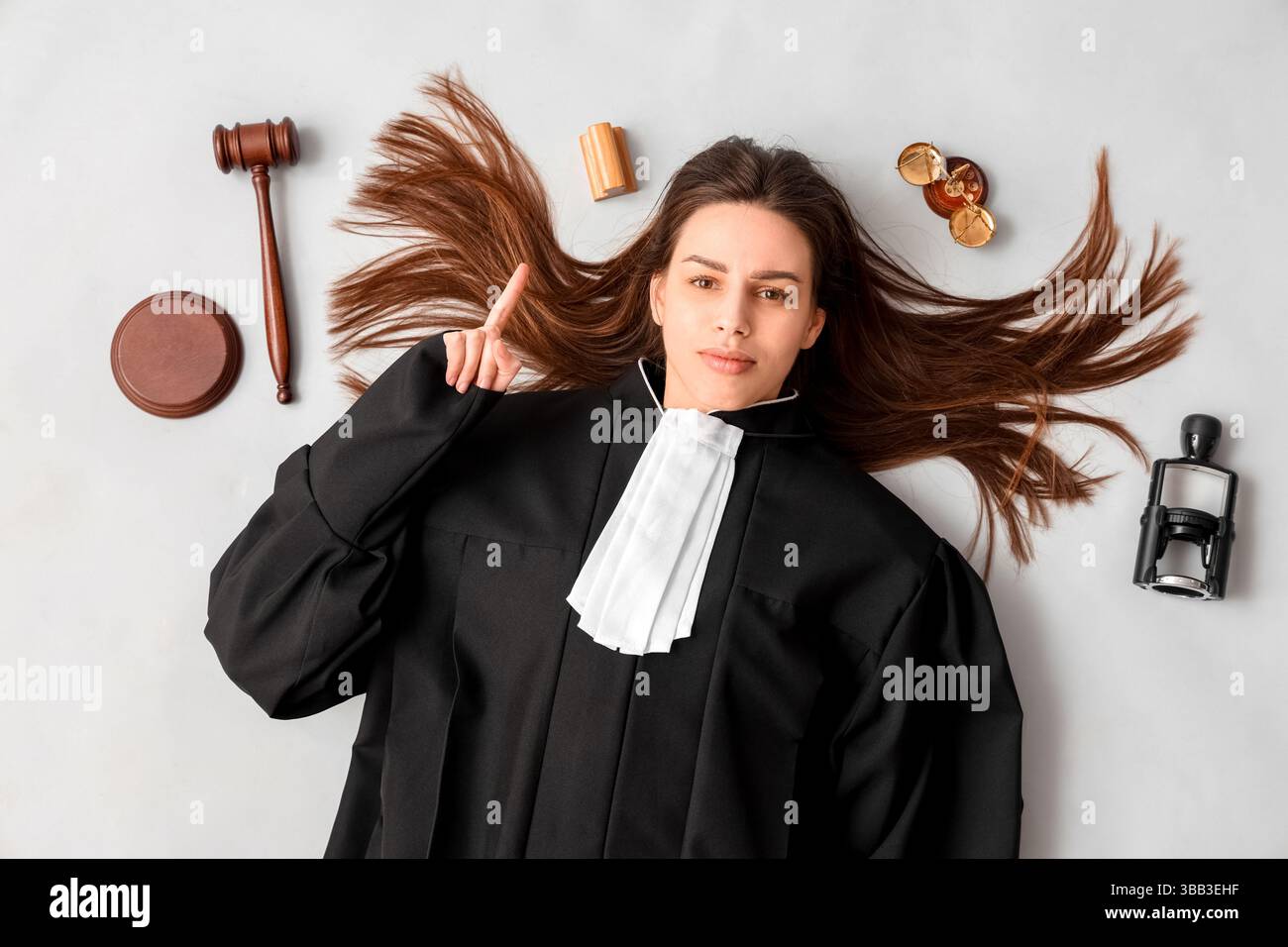 Young female judge with gavel and scales of justice lying and pointing ...