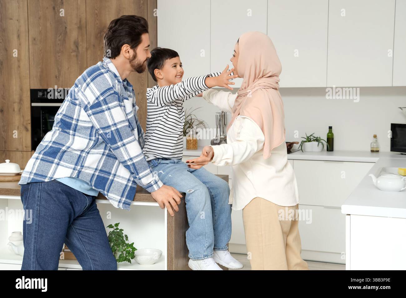 Happy Muslim family hugging in kitchen Stock Photo - Alamy