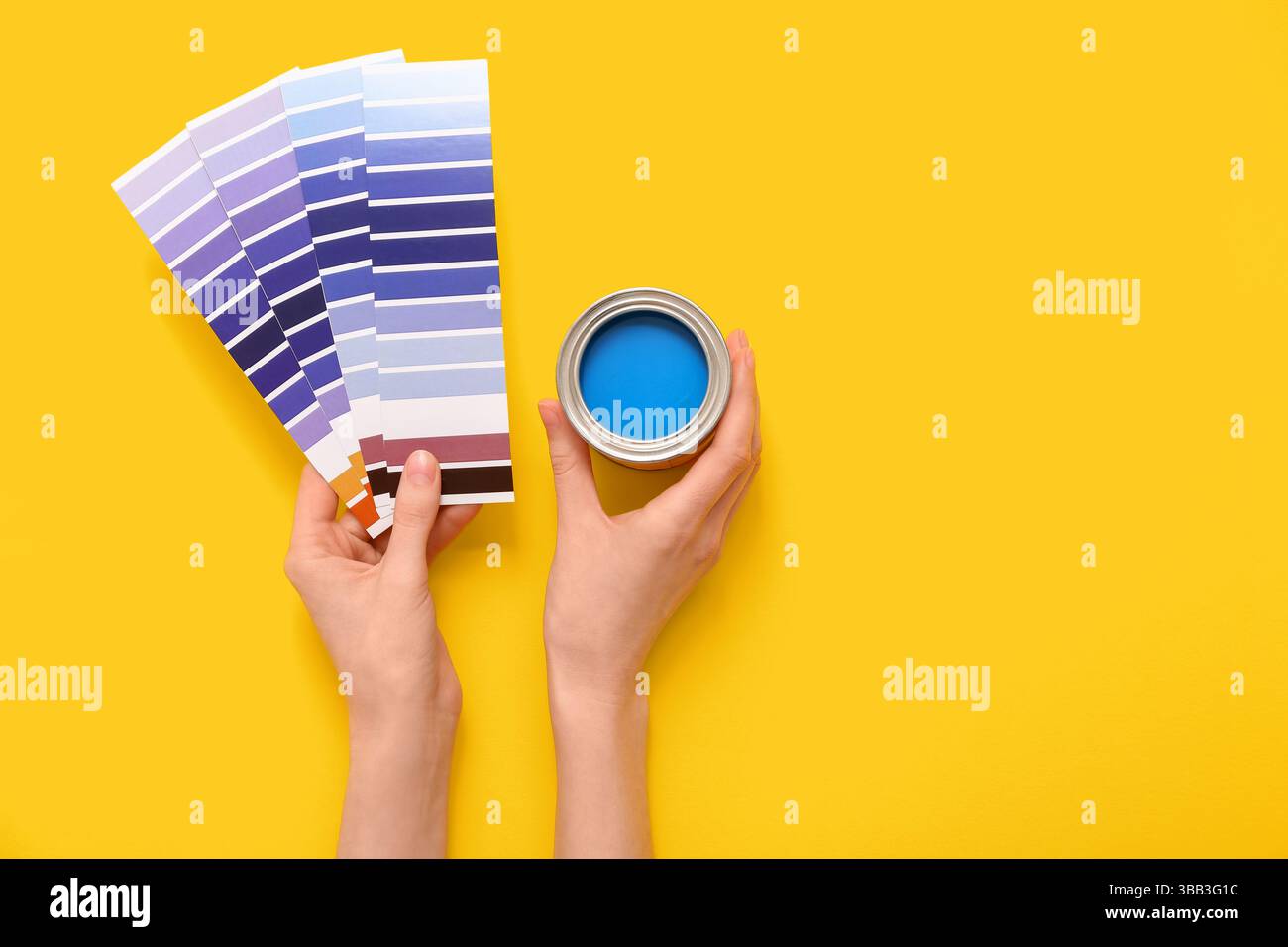 Female hands with can of blue paint and color palettes on yellow ...