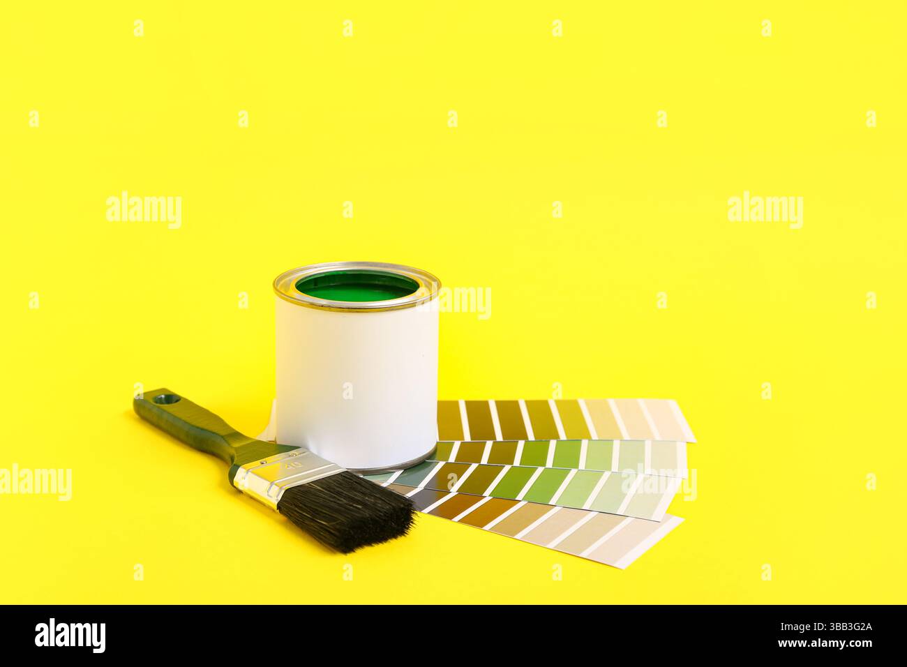 Can of green paint with brush and color palettes on yellow background ...