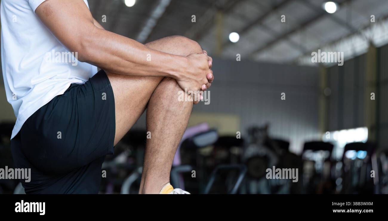 Wellness and Fitness. Young man holding knee during workout in gym for ...