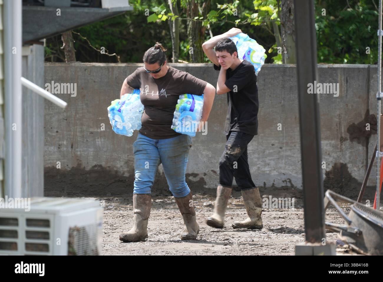People carry drinking water as clean up continues after flooding on ...