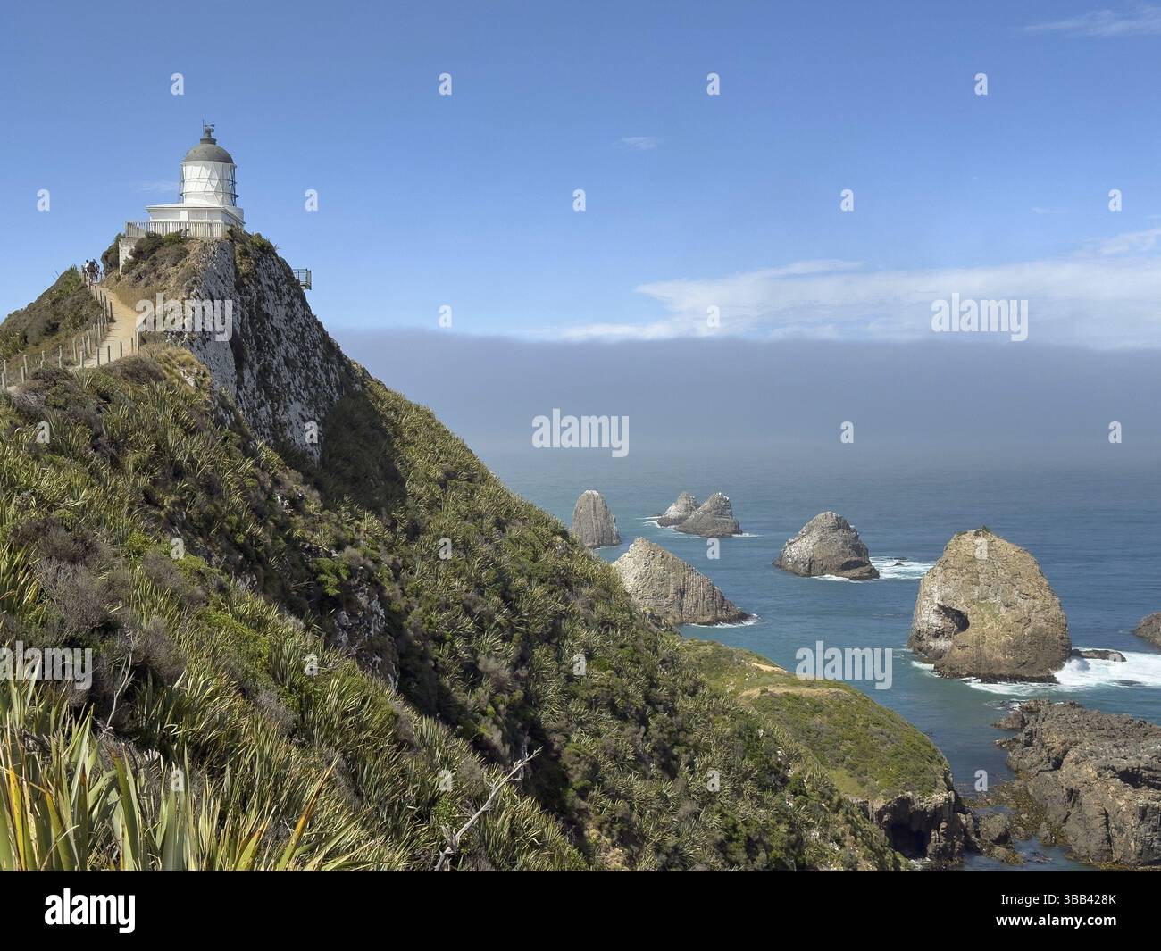 Nugget Point Lighthouse with Nugget Rocks in front of a blue sky, South ...