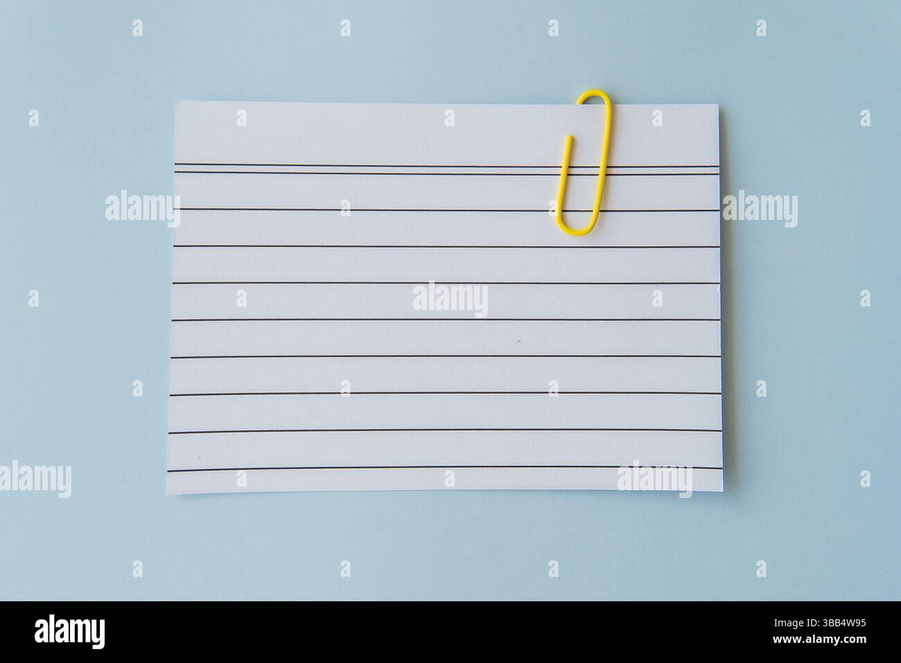 Minimal school paper concept with lined sheet and yellow paperclip on ...