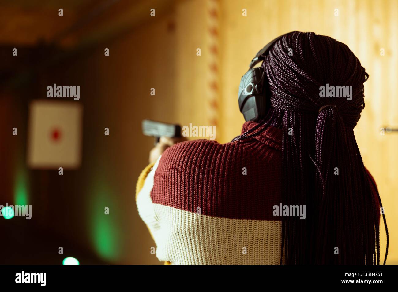Woman in shooting gallery using handgun to hit paper targets with ammo ...