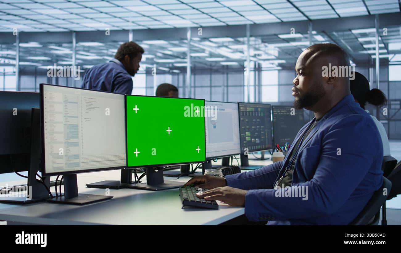 Engineer using green screen computer, working in server farm to optimize it for data processing ...