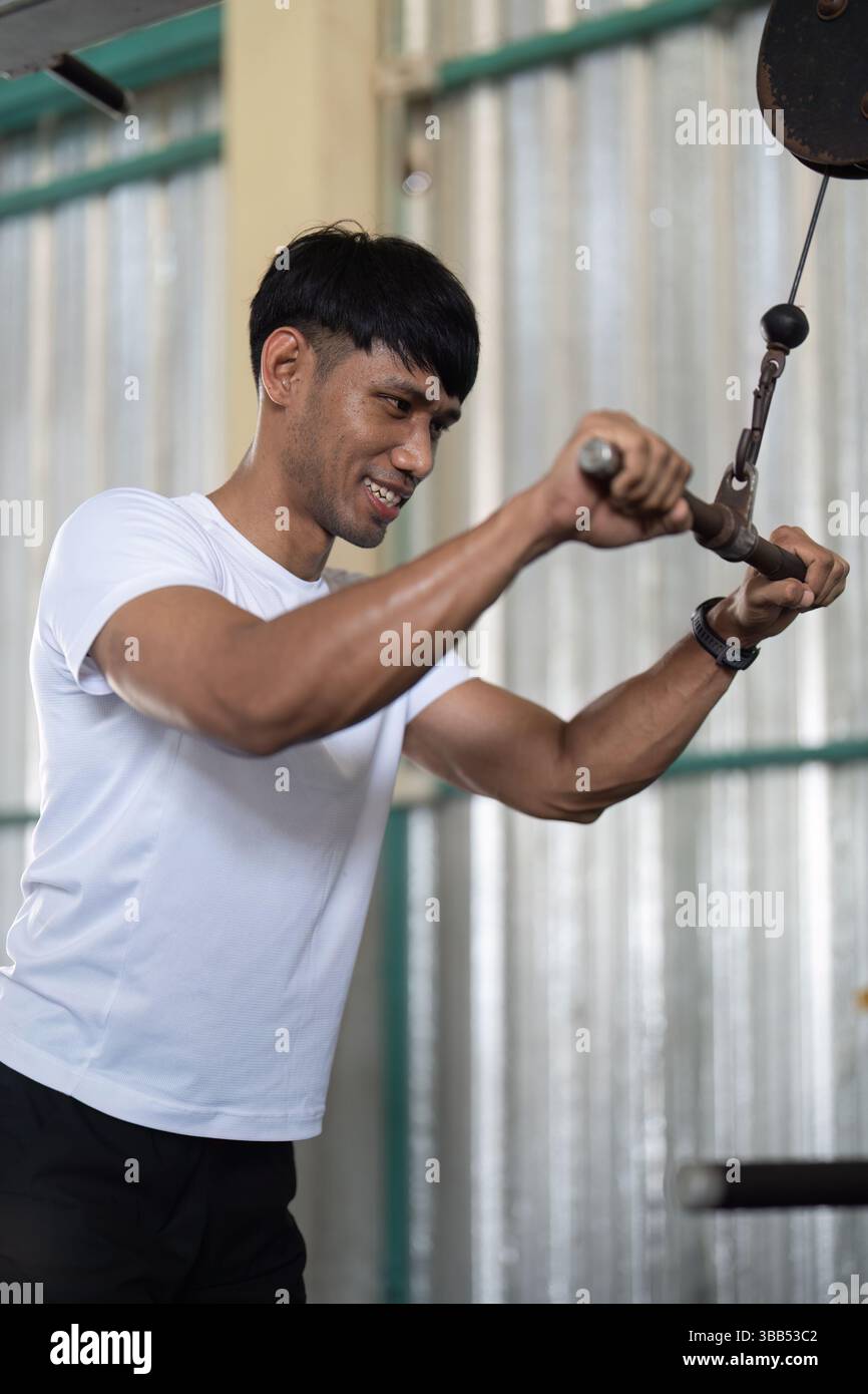 Wellness through Strength Training. Young man engaging in cable pull ...