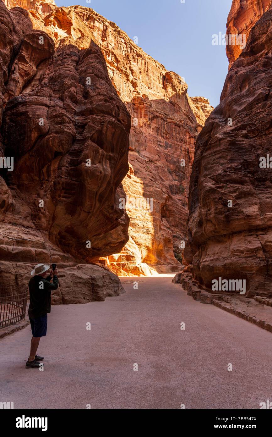 Tourists provide scale to the massive narrow gorge of the Siq entering ...