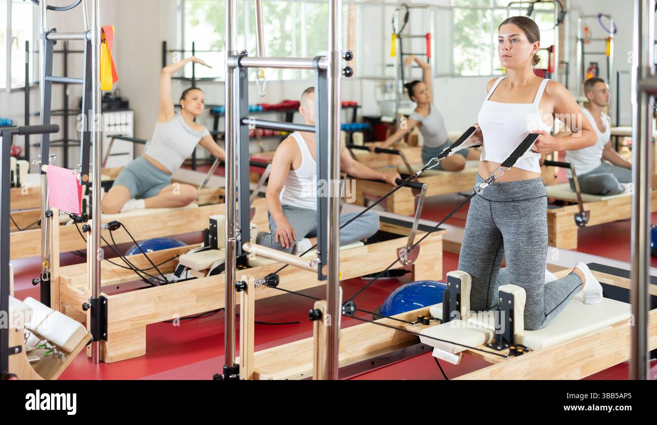 Young girl doing arm exercises on cable reformer device Stock Photo - Alamy