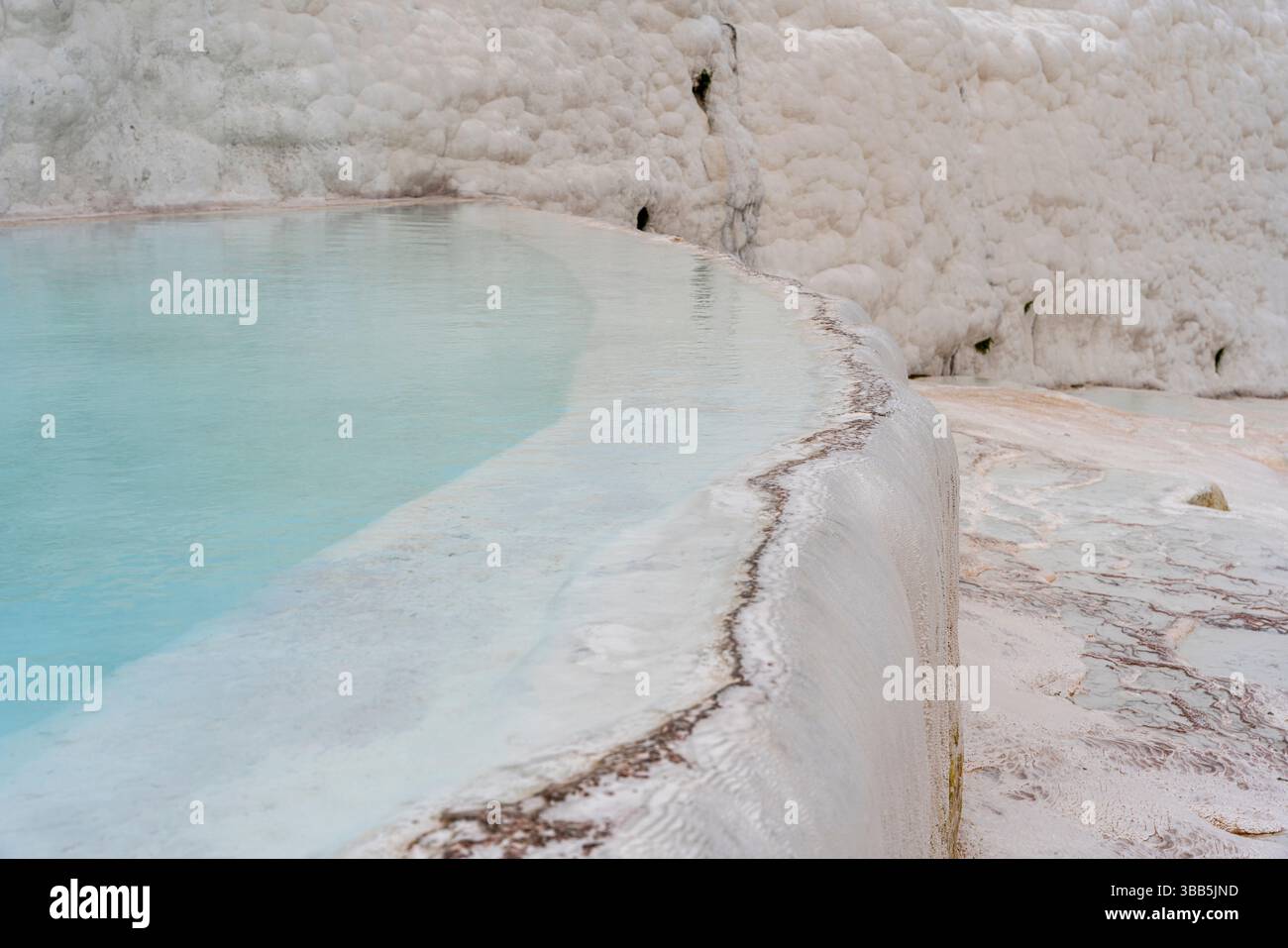 A close view of the smooth, white travertine edge and blue thermal pool ...