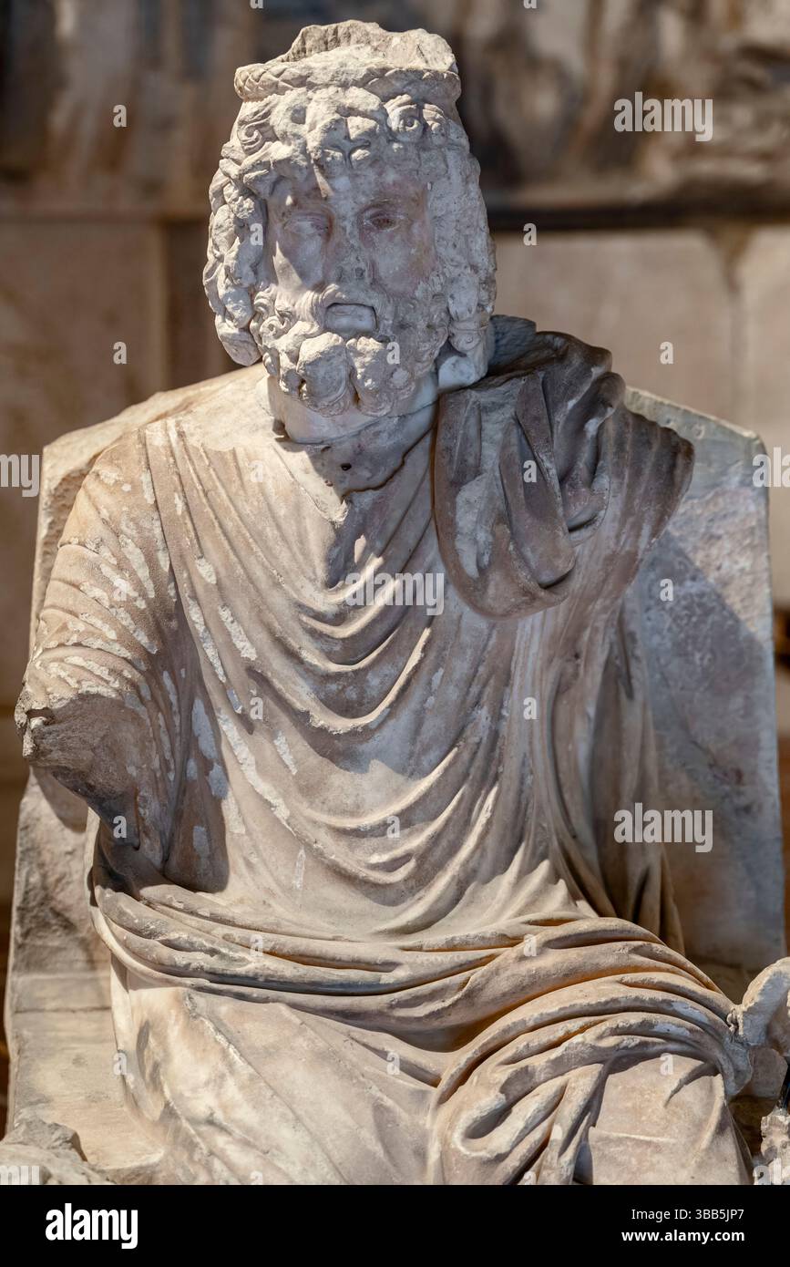 A damaged marble statue of Hades from Hierapolis sits against a carved ...
