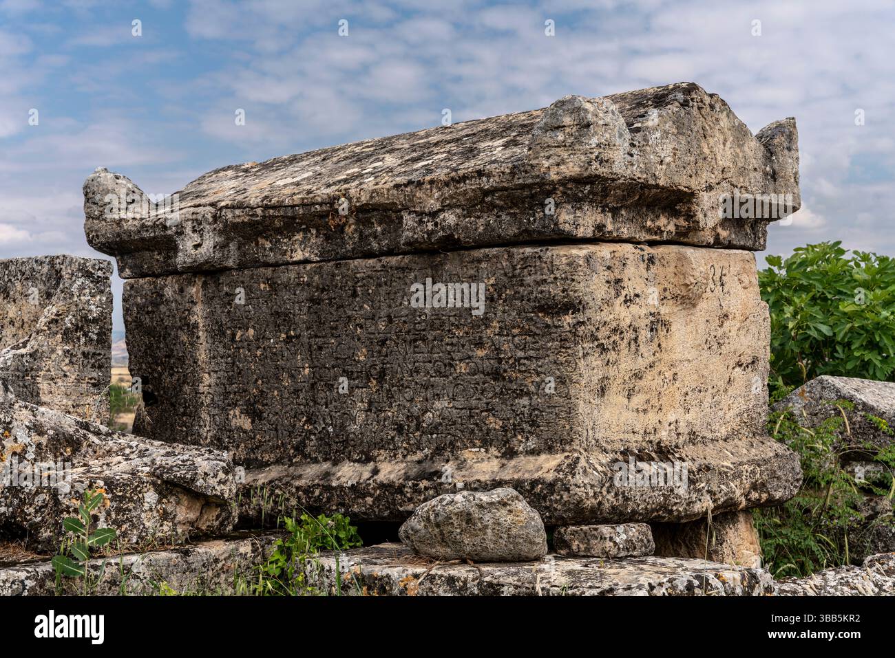 A blocky limestone tomb with a flat roof and weathered facade marks the ...