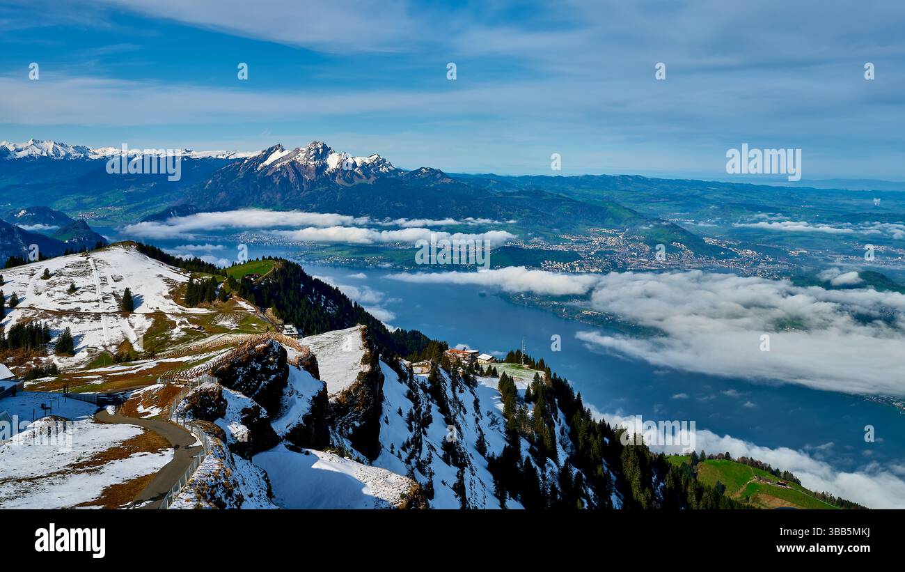 Snow-capped mountains rise beautifully above a serene lake, while wispy ...