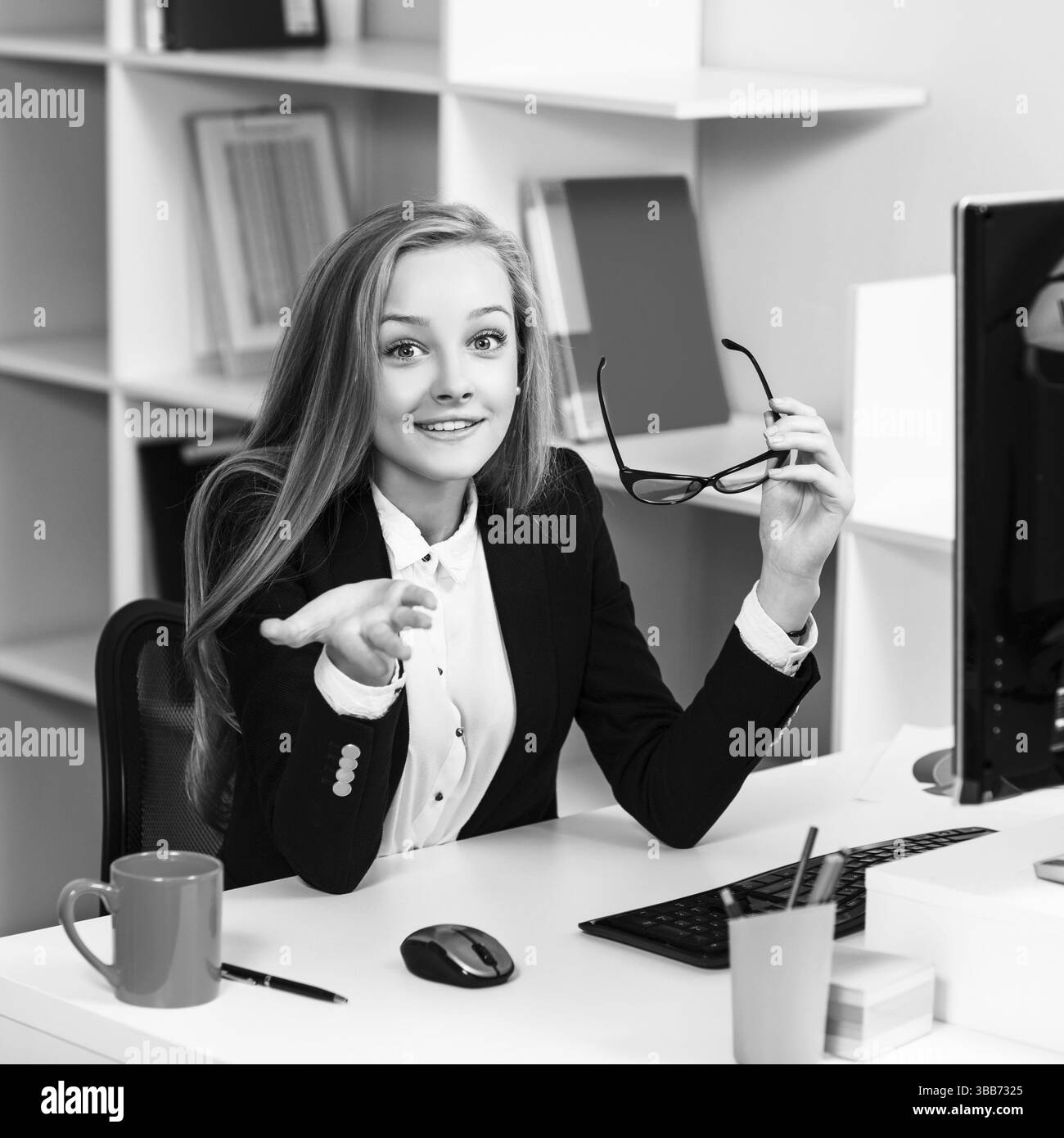 Young pretty business woman sitting at the desk with computer in blue ...