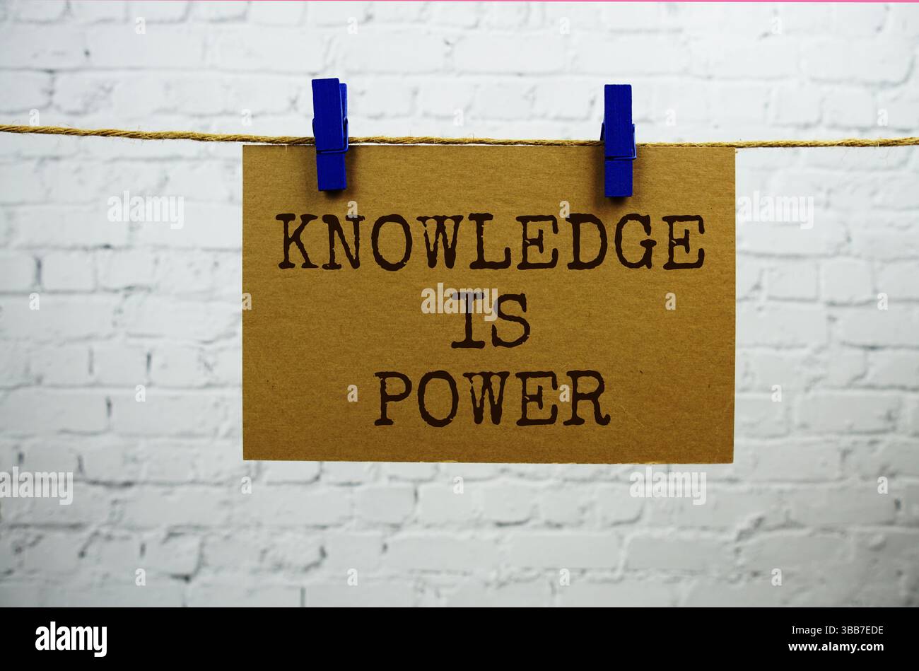 Knowledge is power text on paper card hanging with rope on white brick ...