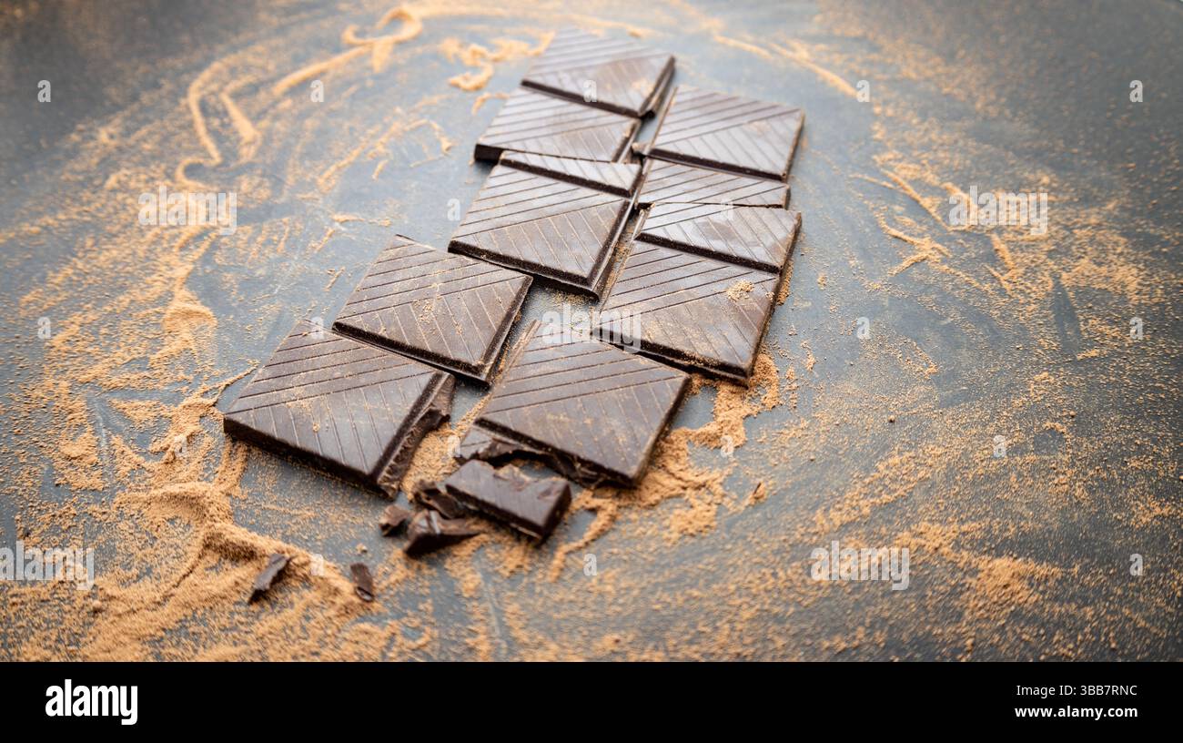 Chocolate bar cut in pieces with chocolate powder around Stock Photo ...