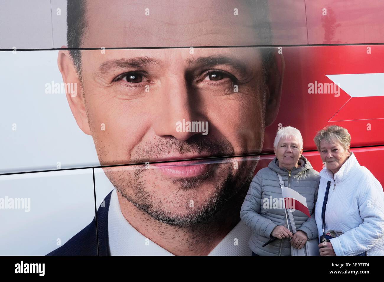 Two women stand next to a campaign poster of Warsaw Mayor Rafał ...