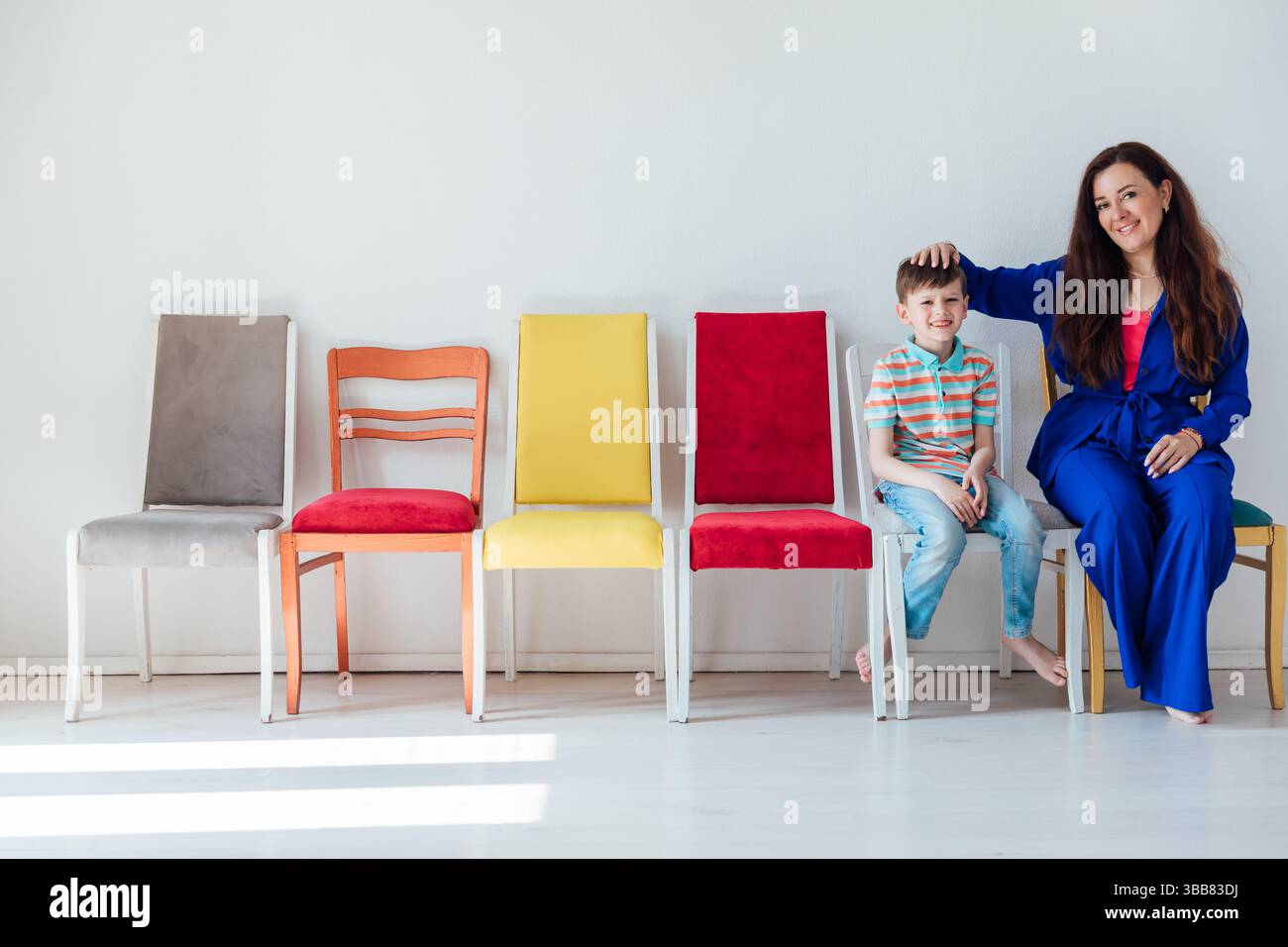 Woman and boy sitting on different chairs in room Stock Photo - Alamy