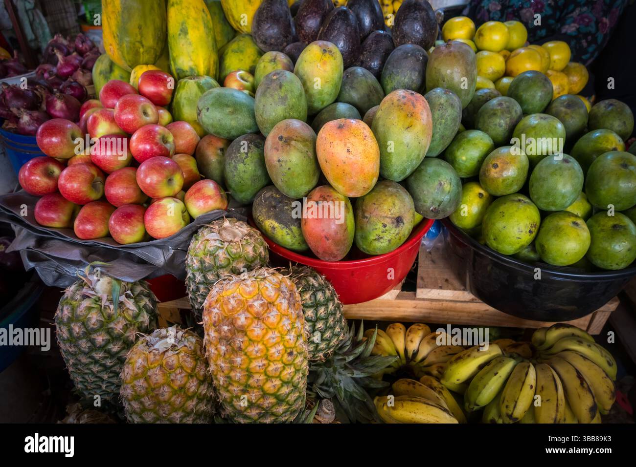 An outdoor market selling fresh produce including bananas, mangoes, and ...