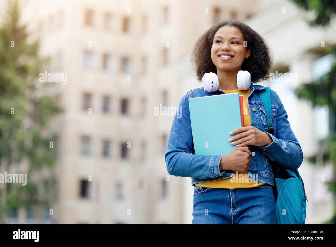 Smiling African American female student walking outdoors at campus ...